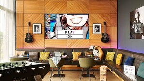 Uma sala de estar moderna com mesa de futebol, sofá e televisão exibindo o texto PLAY ON.