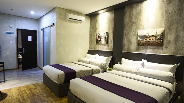 Quarto de hotel com duas camas, piso de madeira, ar condicionado e uma porta.
