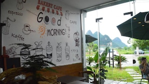 Café e padaria com um mural na parede mostrando desenhos sobre café e os dizeres 'Bom dia!' e 'Espresso'.