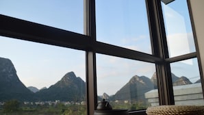 Vista pela janela, com um tapete tecido e uma chaleira sobre a mesa.