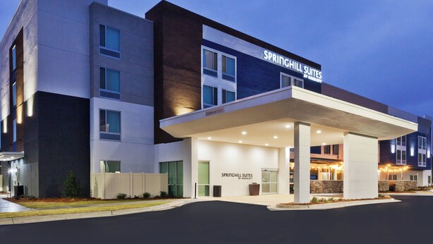 Um hotel moderno com destaque para a sinalização da Springhill Suites by Marriott, apresentando um design limpo e contemporâneo, entrada coberta e janelas visíveis.