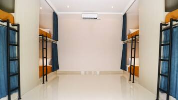 Quarto de hotel com beliches, teto branco e unidade de ar condicionado central.