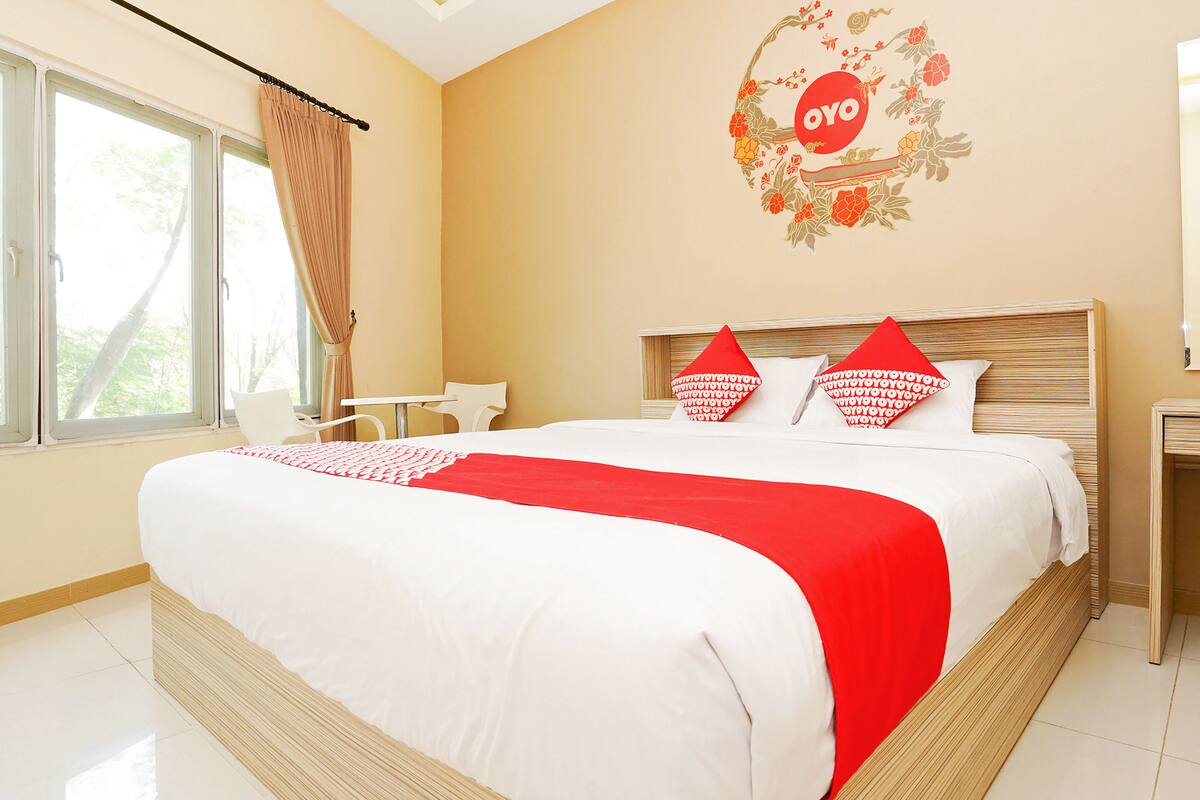 Quarto de hotel com uma cama grande, uma mesa e uma cadeira.