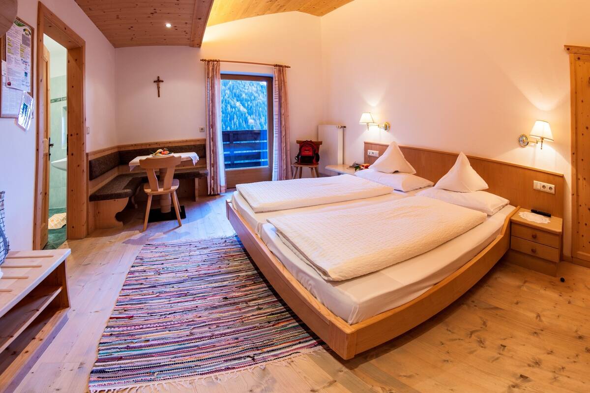 Quarto de hotel com uma cama grande, uma escrivaninha e vista para uma paisagem nevada.