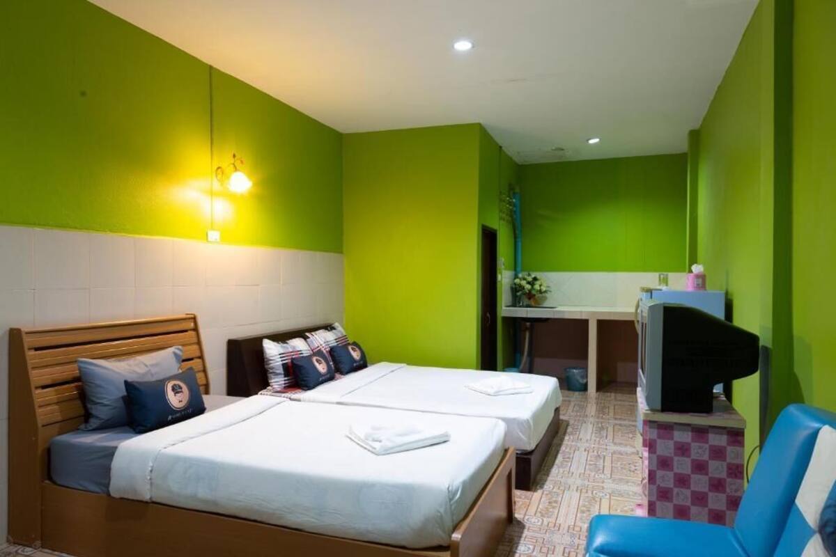 Quarto de hotel com duas camas, uma escrivaninha, uma cadeira e uma televisão.