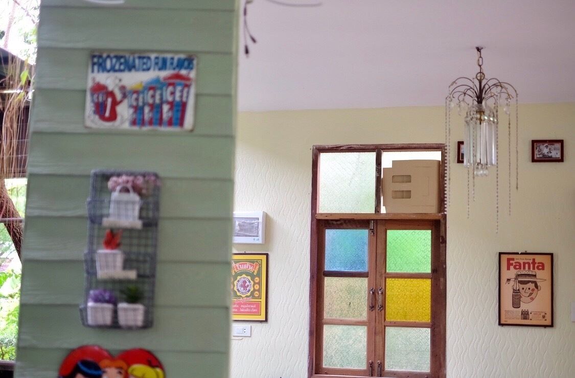 Um quarto com porta de madeira, um candelabro e diversas decorações nas paredes, incluindo um cartaz de palhaço e uma placa da Fanta.