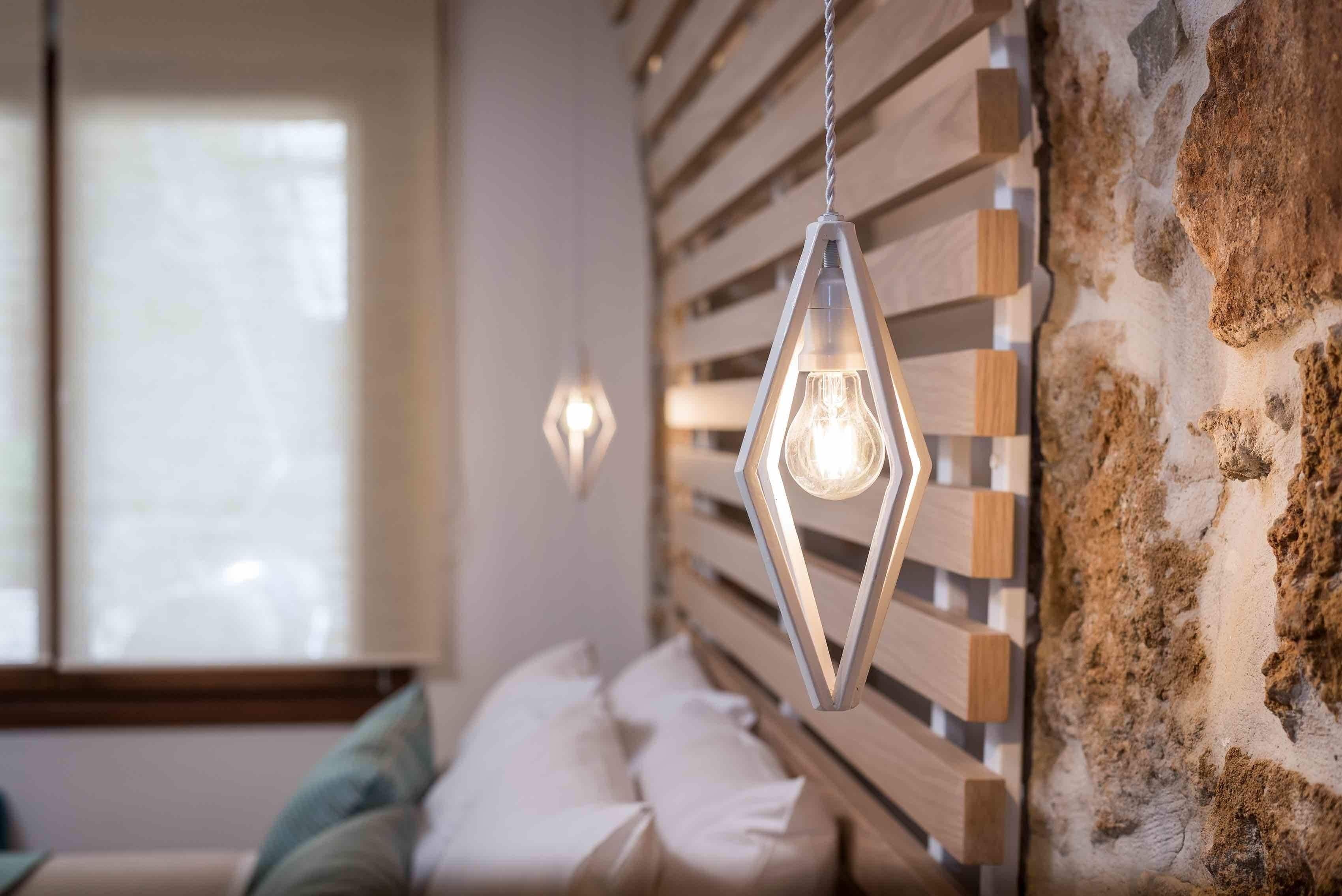 Um interior moderno com parede de ripas de madeira e parede de destaque em pedra, um banco de madeira com almofadas e um lustre.