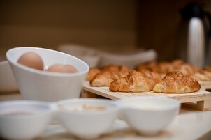 Um cenário de café da manhã com croissants e uma tigela de ovos.