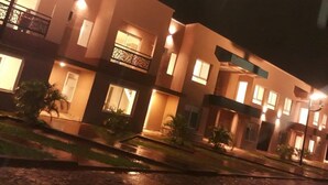 Um edifício alto com janelas e varandas iluminadas à noite.