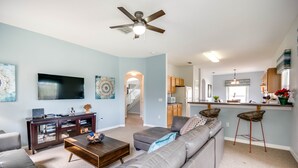 Uma sala de estar moderna com um sofá modular cinza, uma mesa de centro e uma televisão de tela plana em um suporte de madeira.