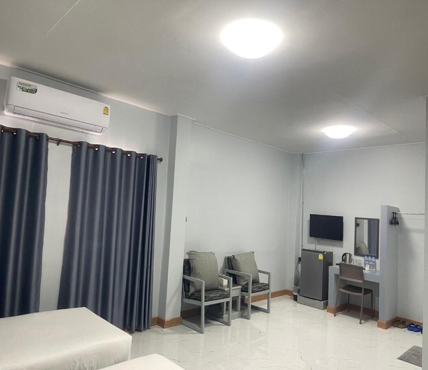 Quarto de hotel com cama, escrivaninha, cadeira, televisão e ar condicionado.