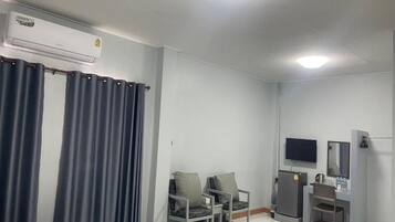 Quarto de hotel com cama, escrivaninha, cadeira, televisão e ar condicionado.