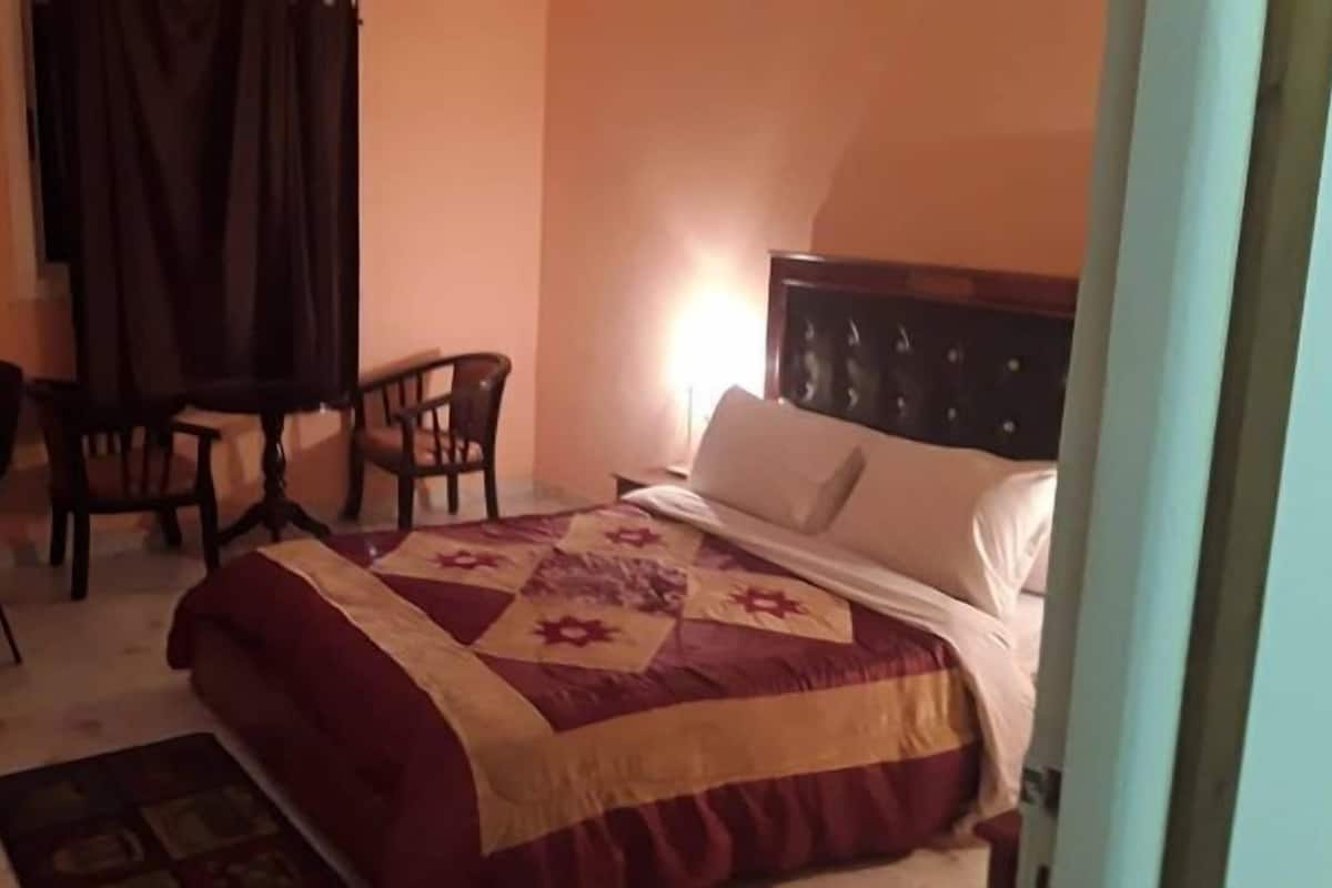 Quarto com uma cama, escrivaninha e duas cadeiras.