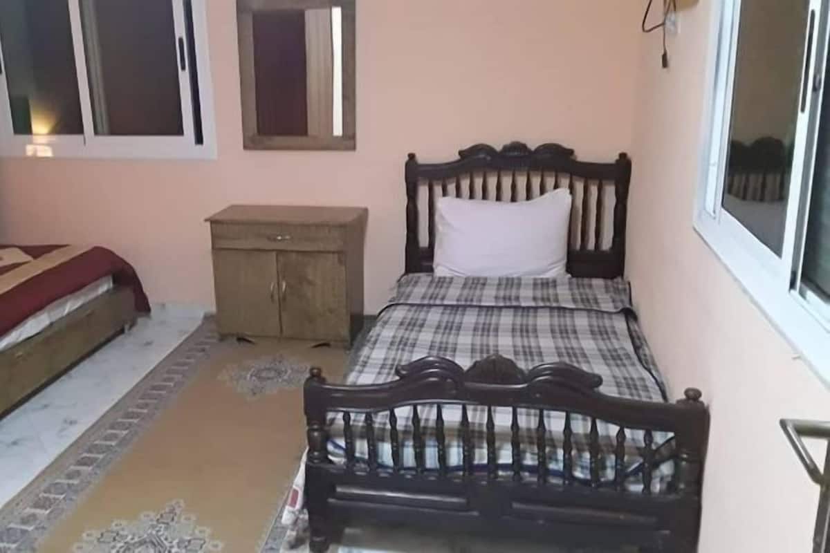 Quarto com cama, guarda-roupa e janela.