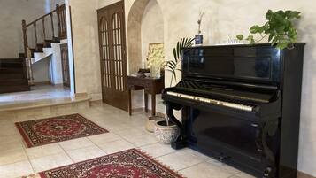 Uma sala de estar ampla com um piano de cauda, uma escadaria e um arco decorativo.