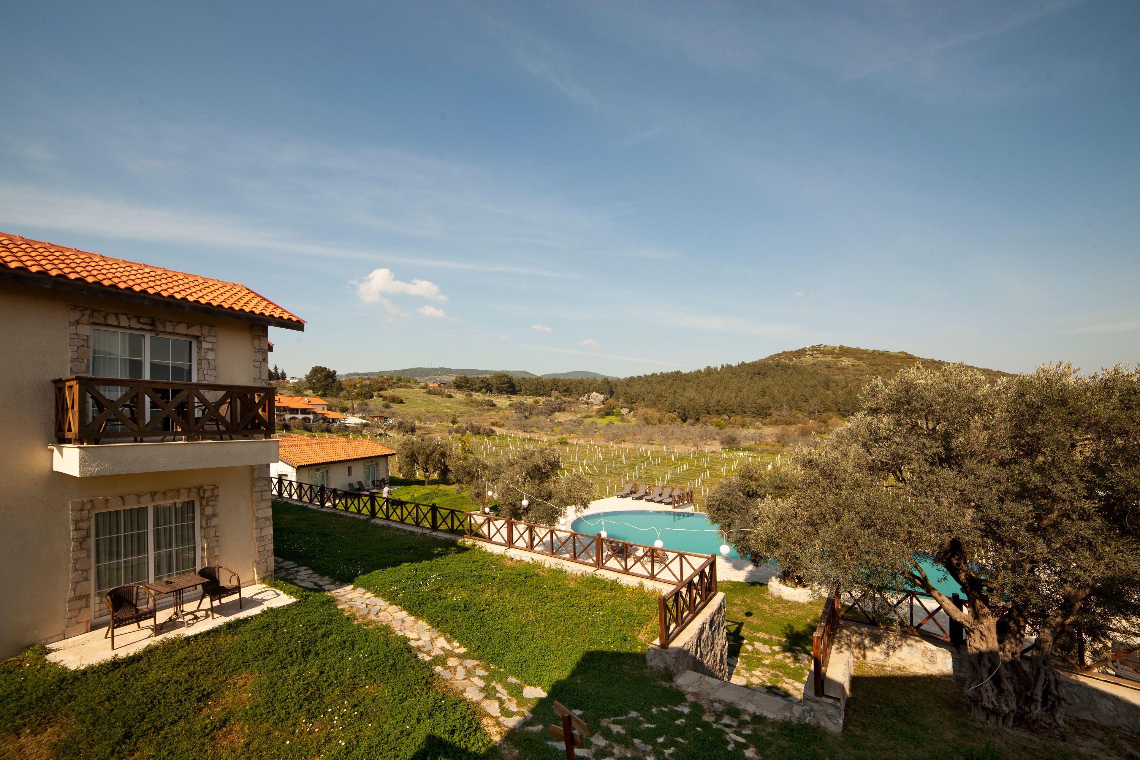 Uma villa com piscina, varanda e vista para o campo.