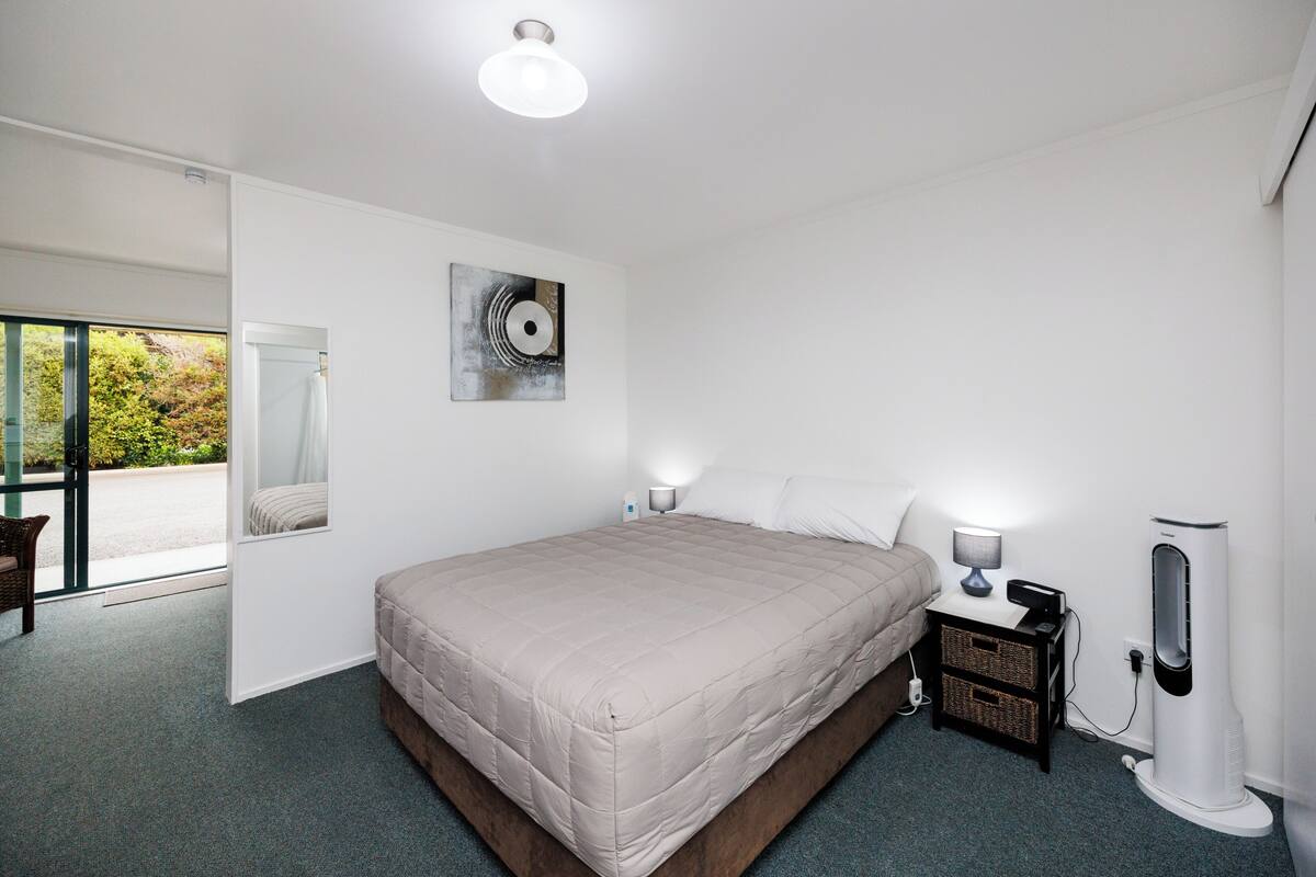 Quarto com cama, luminárias de cabeceira, aquecedor, uma obra de arte na parede e janela com vista.