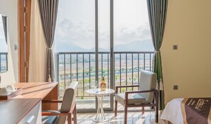 Quarto de hotel com varanda, mesa de jantar, duas cadeiras e uma cama.