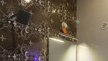 Um banheiro com revestimento de azulejos decorativos, uma pia redonda, um espelho e um porta-toalhas.