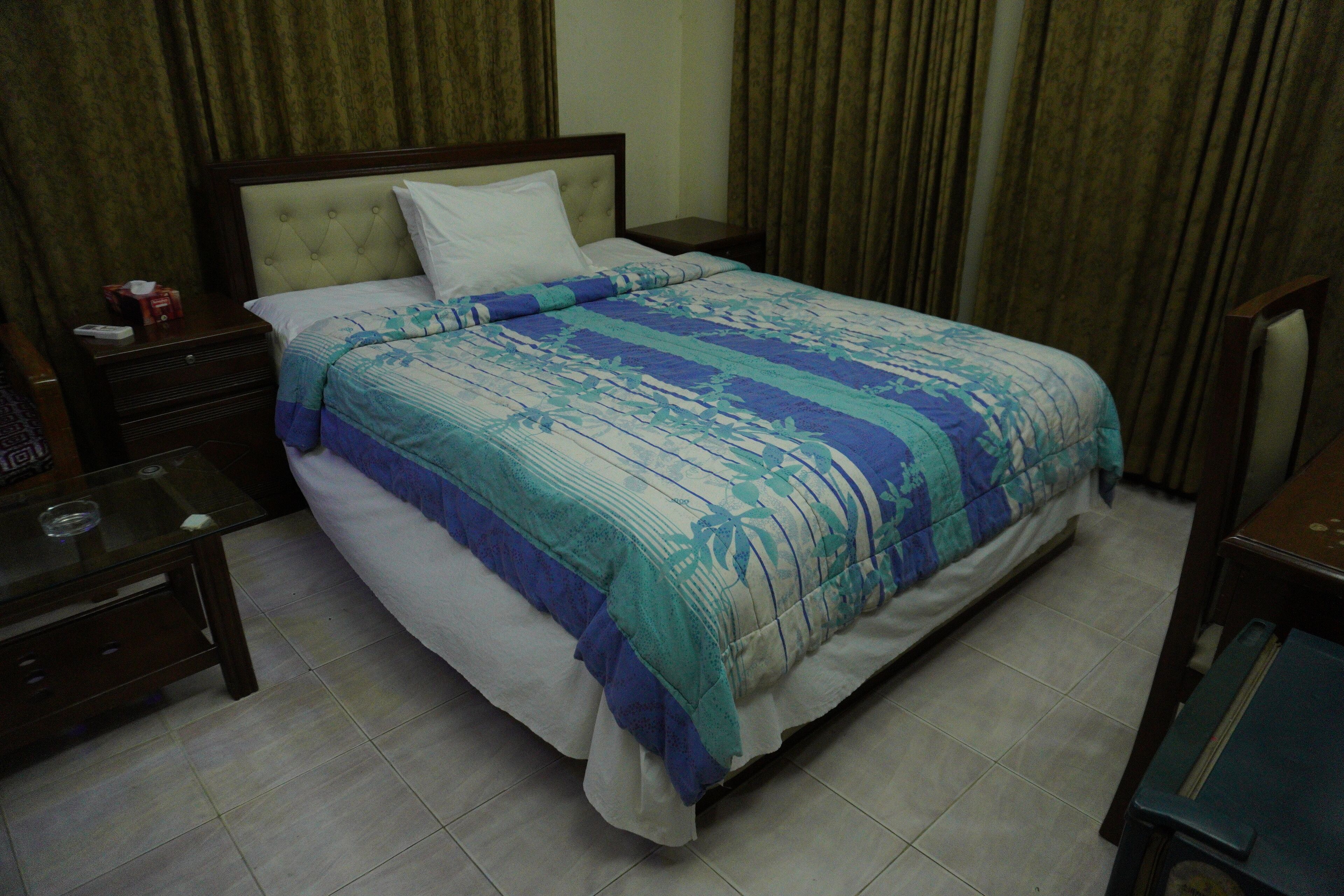 Quarto de hotel com uma cama, uma mesa de cabeceira, uma pequena mesa e uma cadeira.
