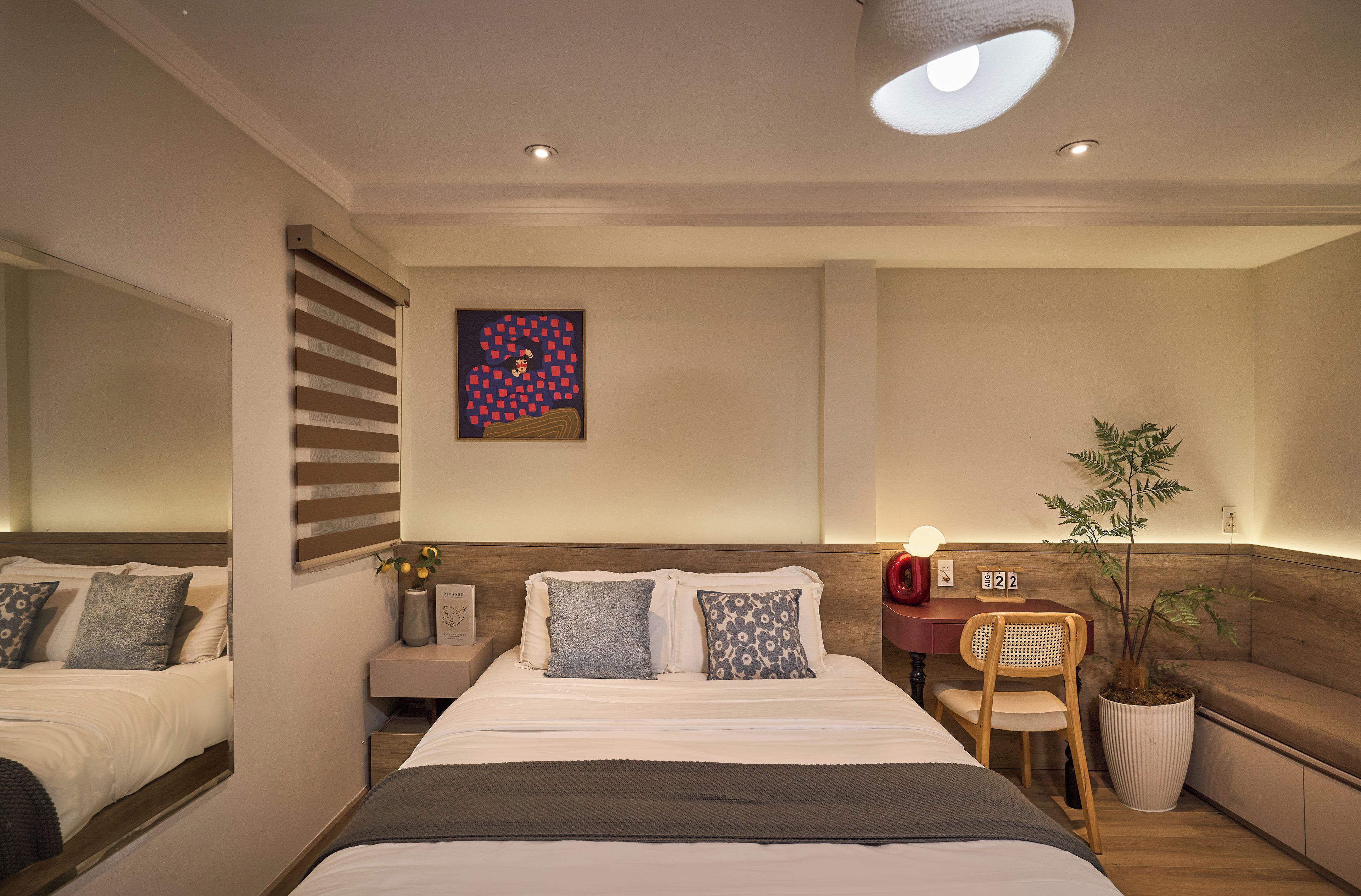 Quarto moderno com uma cama grande, mesas de cabeceira, uma escrivaninha e uma cadeira.