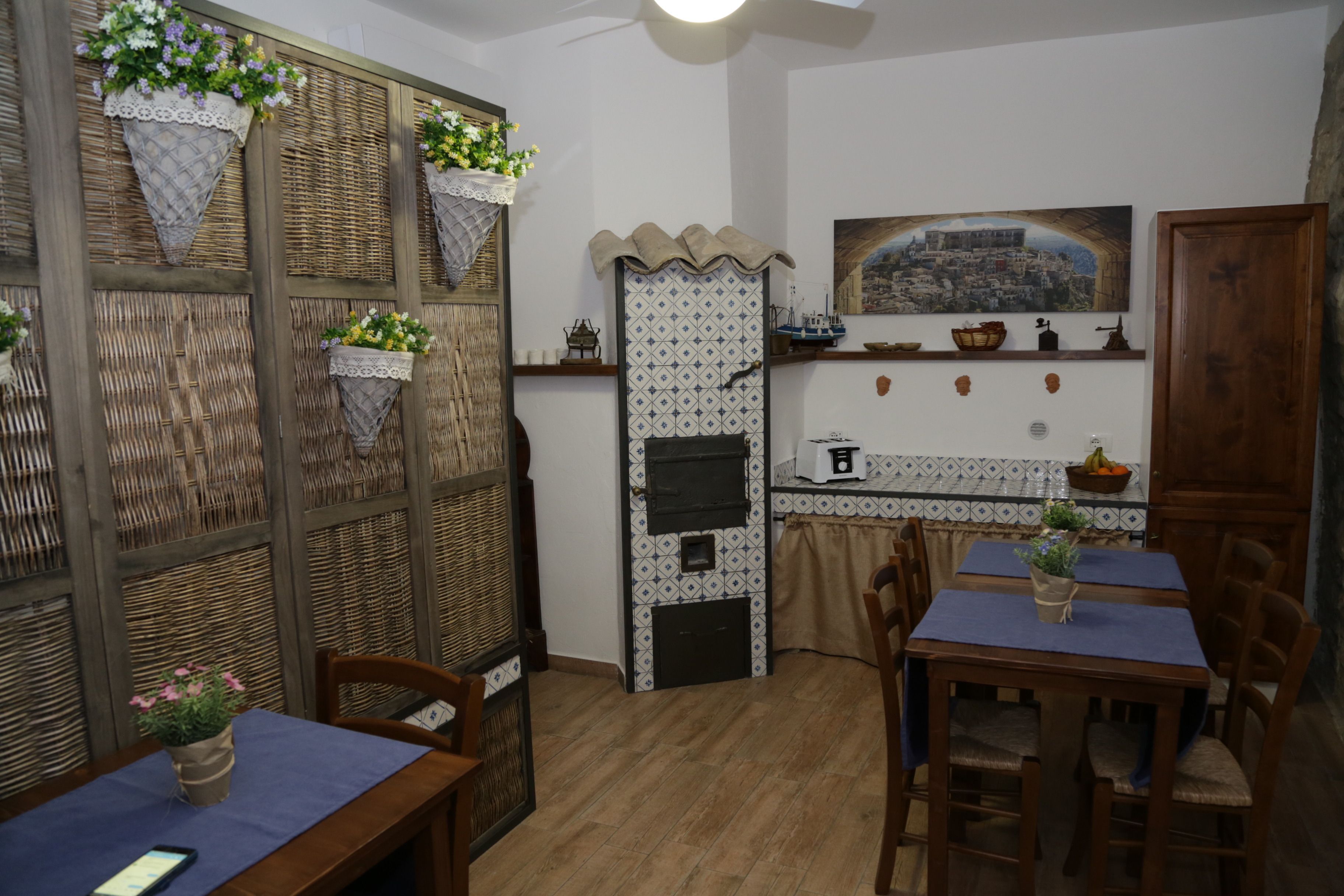 Cozinha acolhedora com mesa e cadeiras de madeira, painel de azulejos e um quadro acima do balcão.