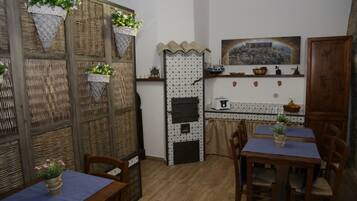Cozinha acolhedora com mesa e cadeiras de madeira, painel de azulejos e um quadro acima do balcão.