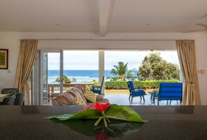 Quarto com vista para o oceano, área de refeições e sala de estar com cadeiras azuis.