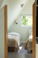 Quarto com duas camas, uma janela e um lustre.