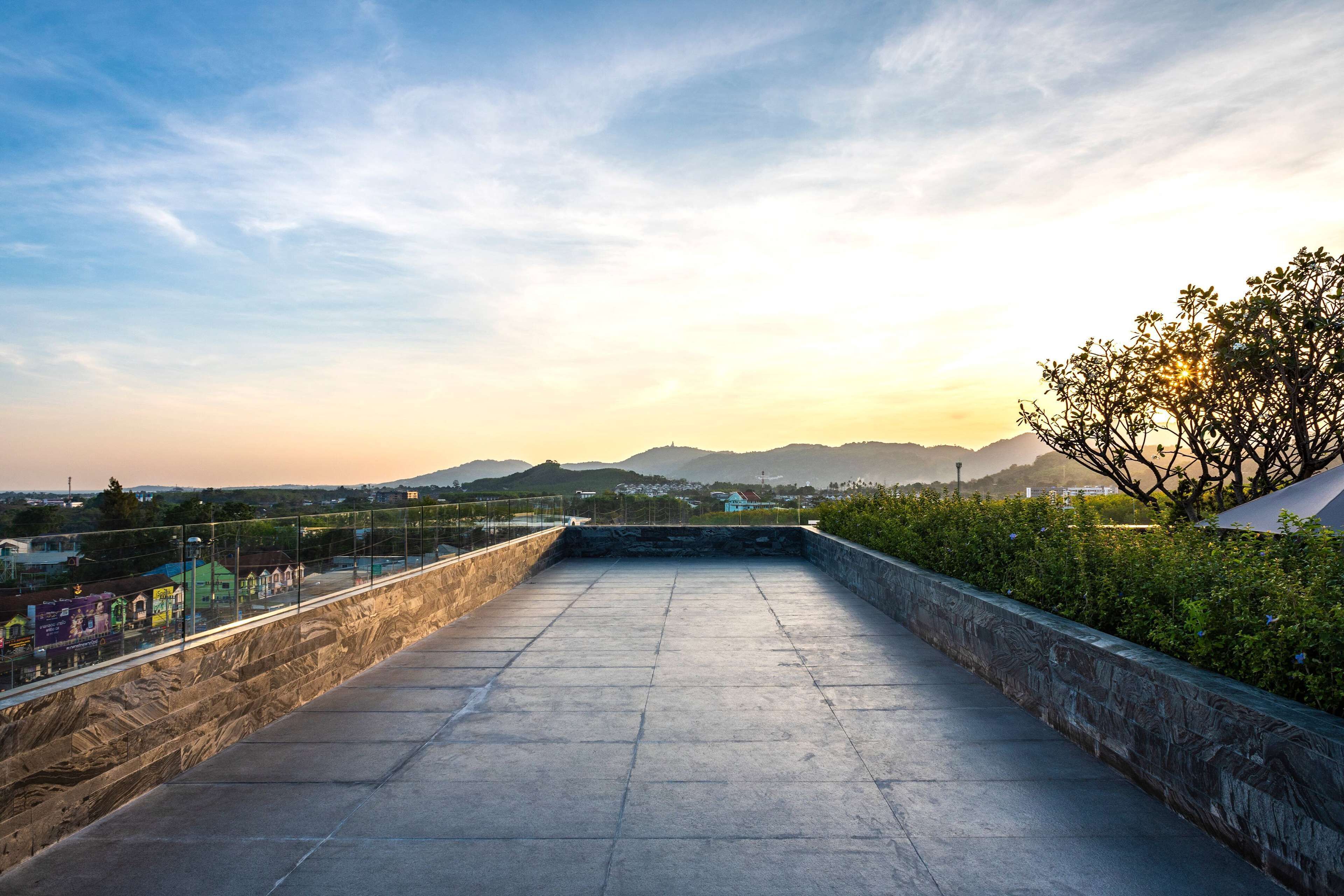Terraço no telhado com vista para montanhas distantes e um pôr do sol.