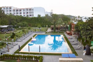 Piscina com espreguiçadeiras e quadra de tênis.
