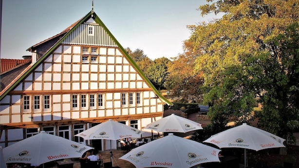 Um edifício tradicional em estilo de enxaimel com área externa e guarda-sóis com o logotipo da Weissbier.