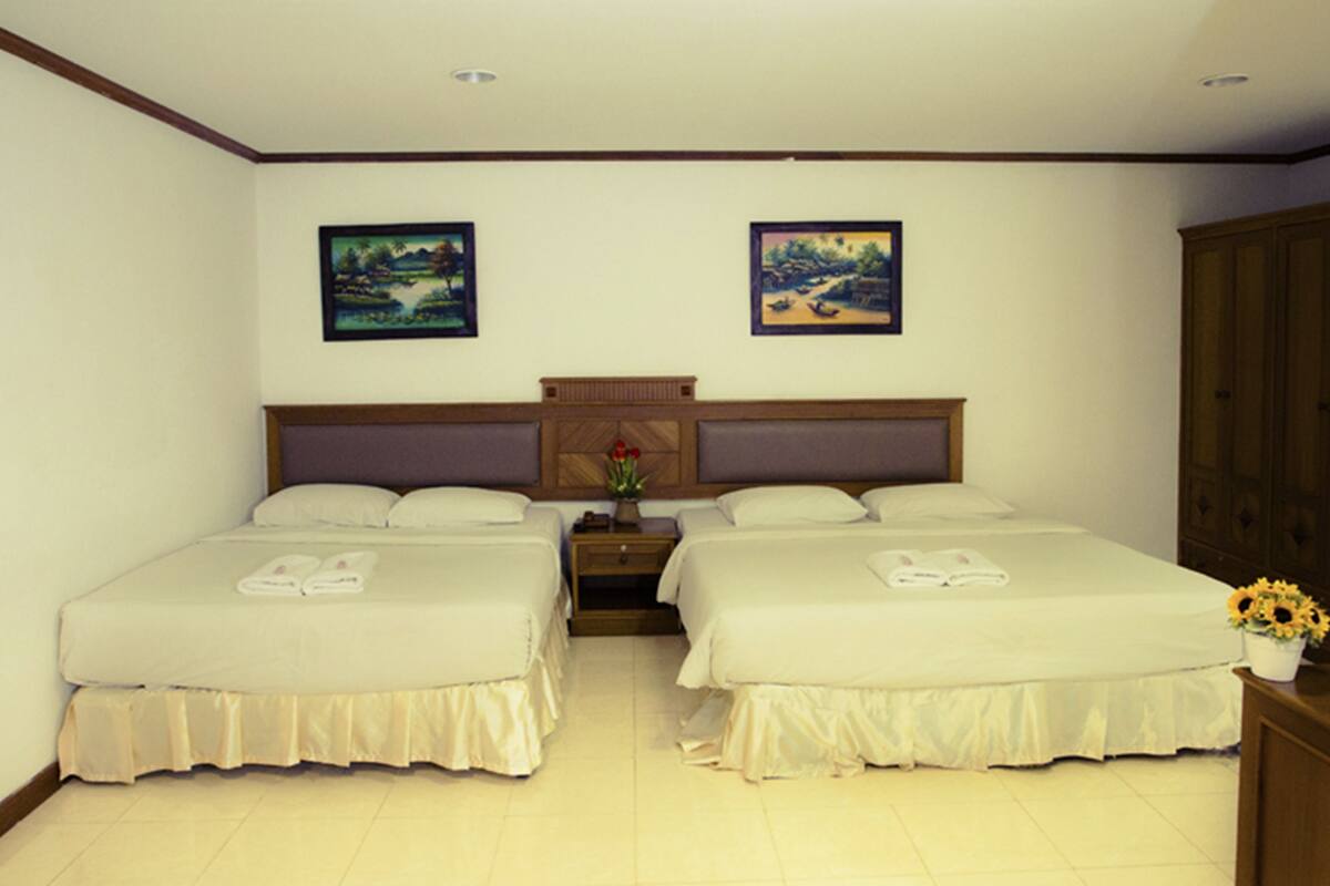 Quarto de hotel com duas camas, uma mesa de cabeceira, um painel de cabeceira de madeira e duas fotos emolduradas na parede.