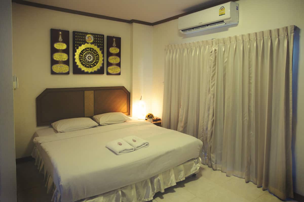 Quarto de hotel com cama, mesa de cabeceira, ar condicionado e uma parede com pratos decorativos.
