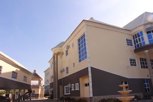 Um edifício de vários andares com fachada bege, janelas grandes e uma fonte central.
