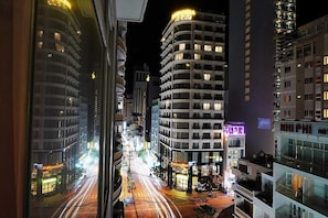 Vista noturna de um horizonte urbano com edifícios modernos, incluindo um hotel chamado 'LegendSea' com sinalização iluminada.