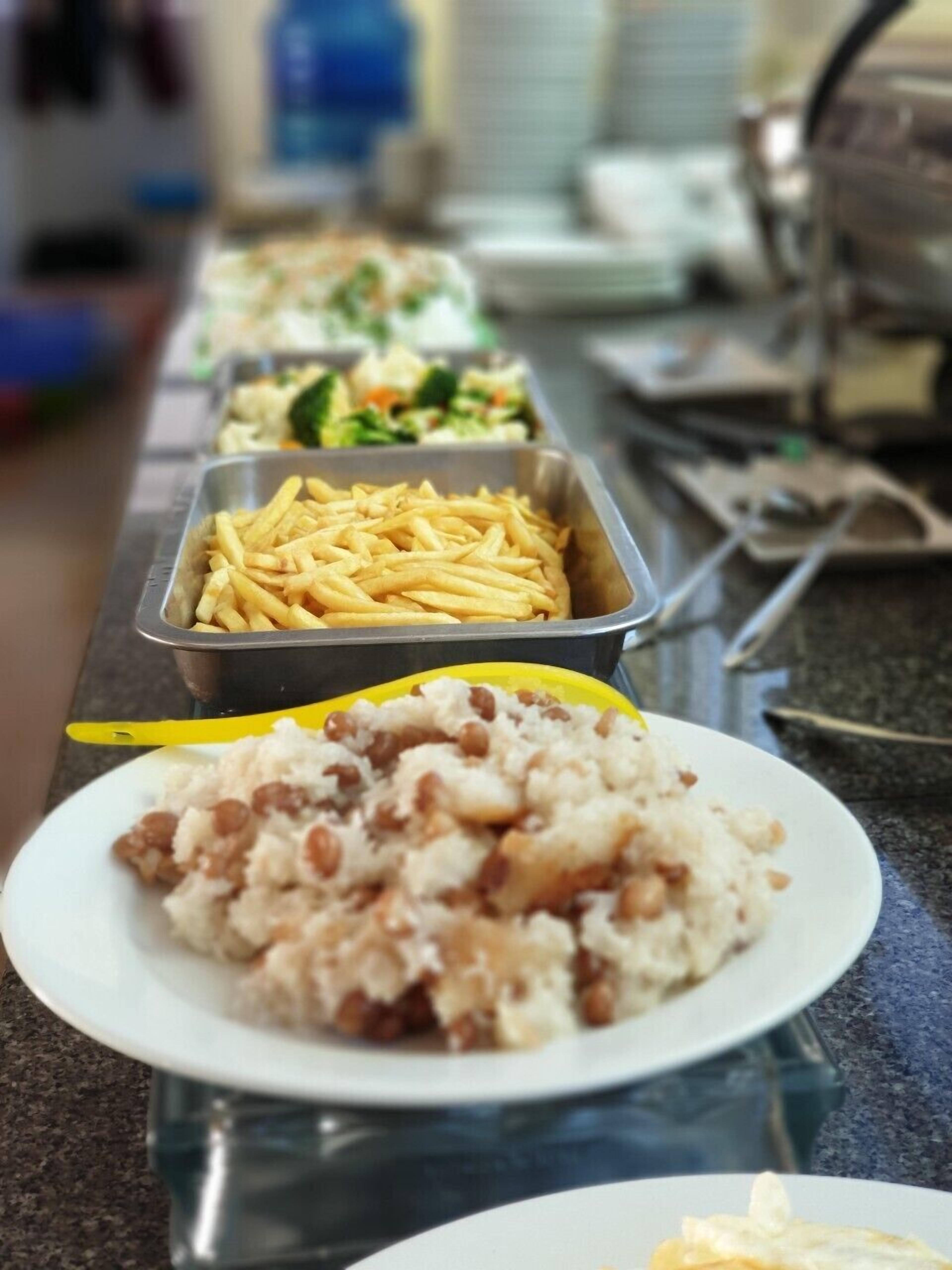 Buffet com diversos pratos, incluindo arroz, batatas fritas e saladas.