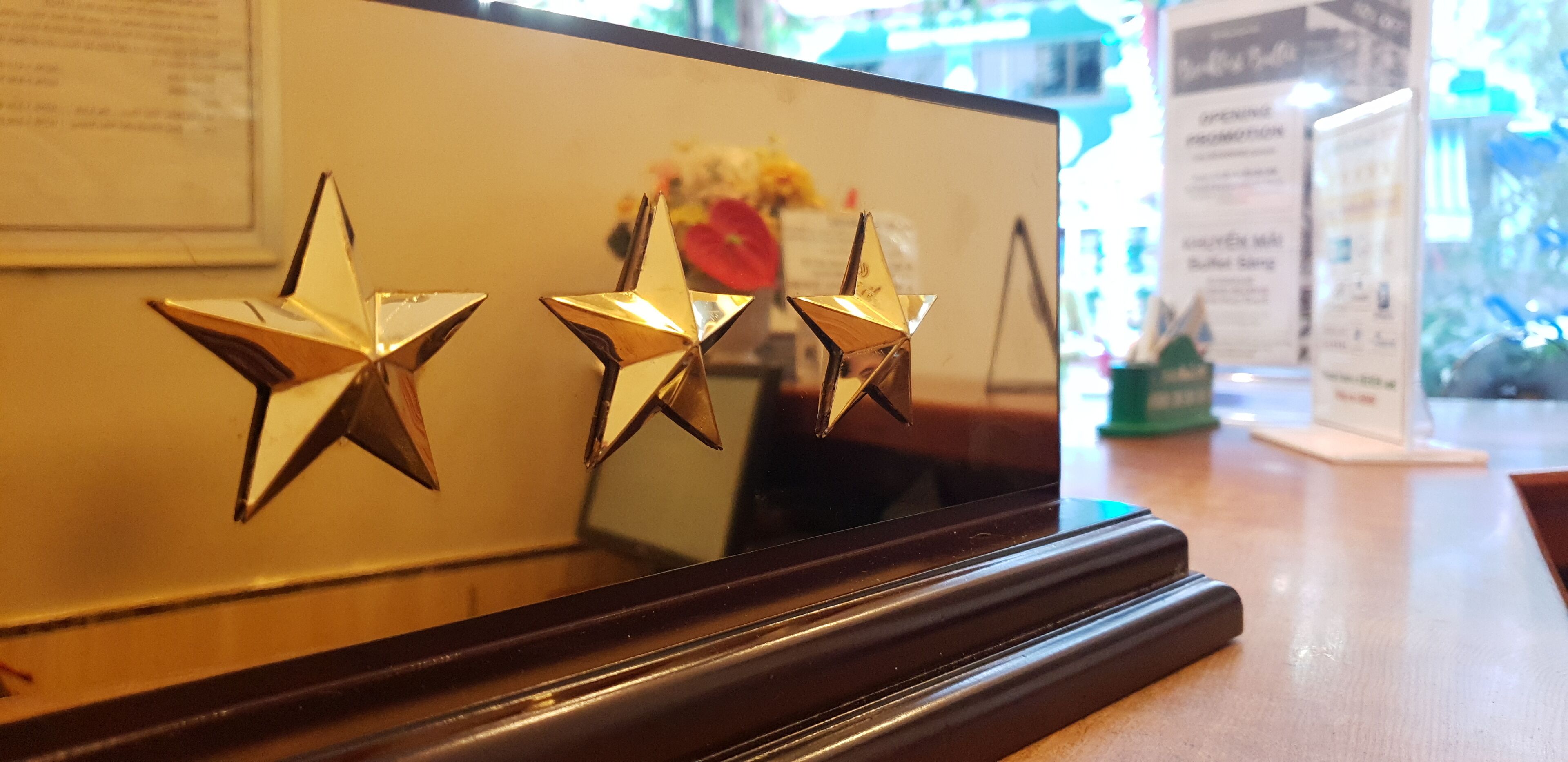 Um balcão de madeira com três estrelas douradas refletidas em uma superfície espelhada.