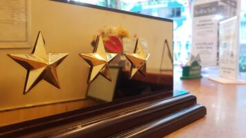 Um balcão de madeira com três estrelas douradas refletidas em uma superfície espelhada.