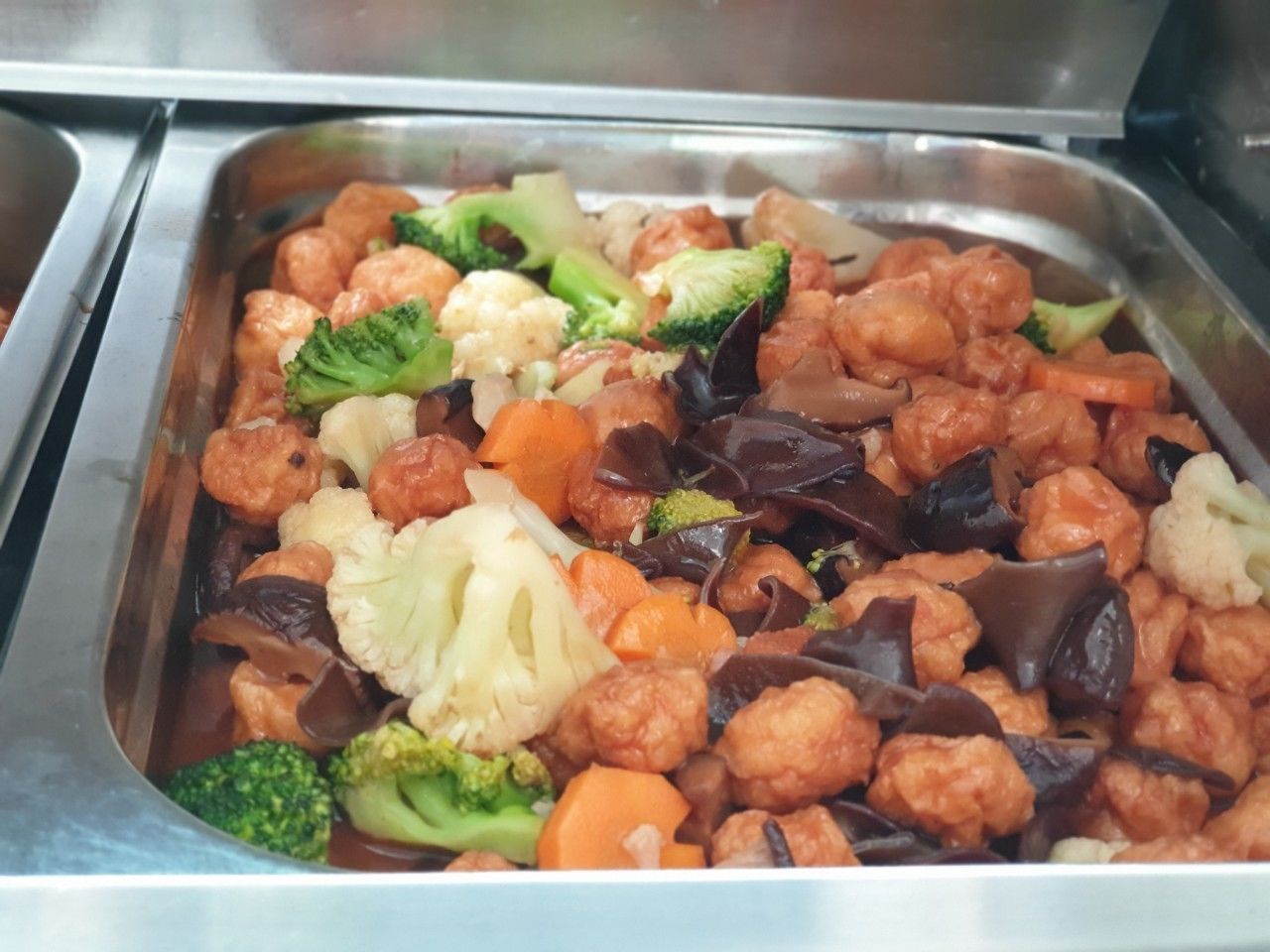 Buffet com diversos vegetais e um prato que parece ser um refogado ou mistura de legumes.