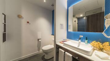 Uma casa de banho moderna com uma sanita, um lavatório branco e um espelho com moldura azul.