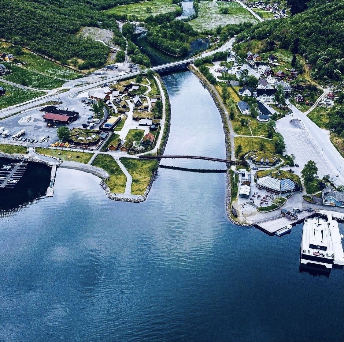 Vista aérea de uma cidade ribeirinha com uma ponte, áreas residenciais e um porto de iates.