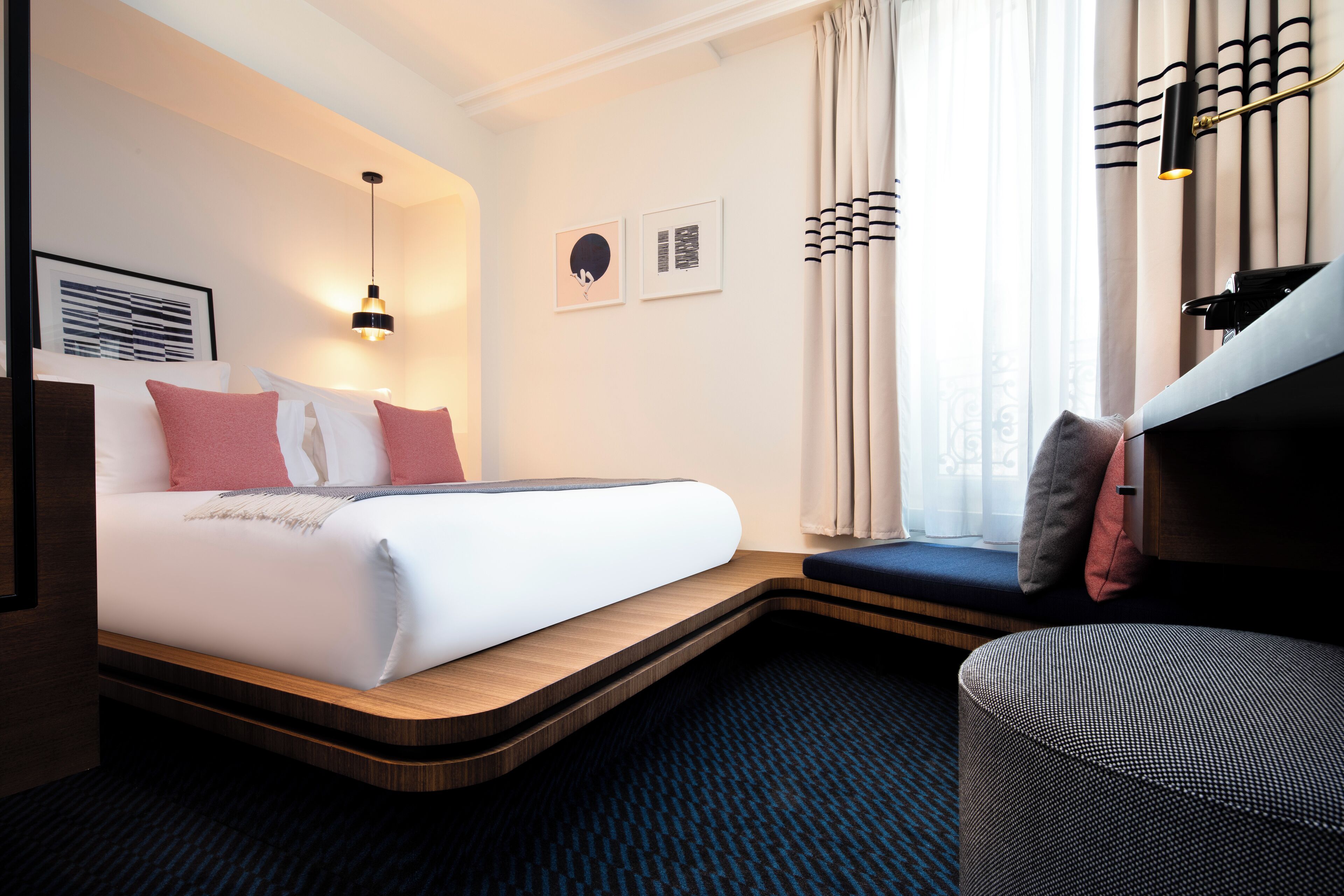 Quarto de hotel moderno com cama, um banquinho, escrivaninha e um piano.