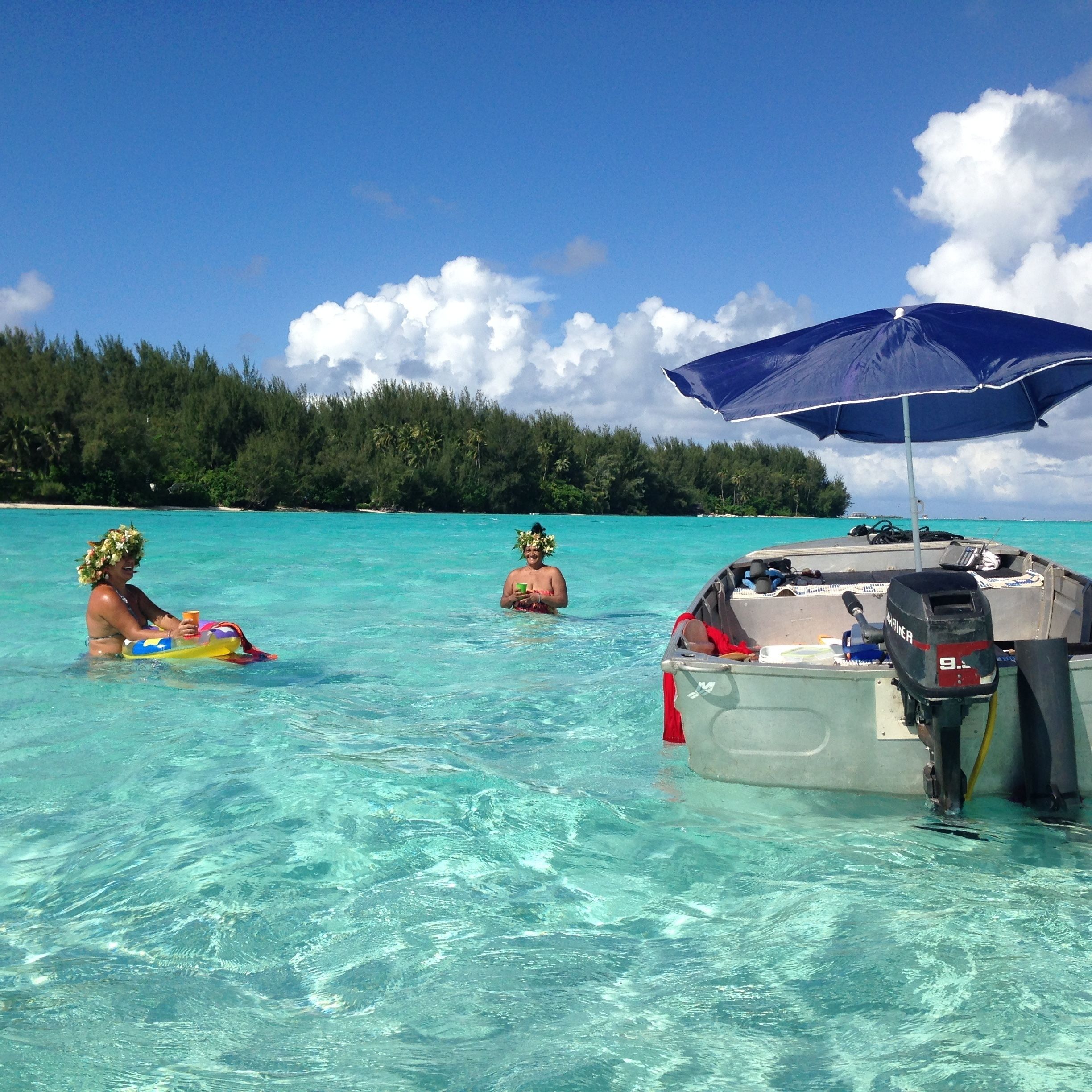 Barco com toldo azul e motor, flutuando em águas turquesa cristalinas.