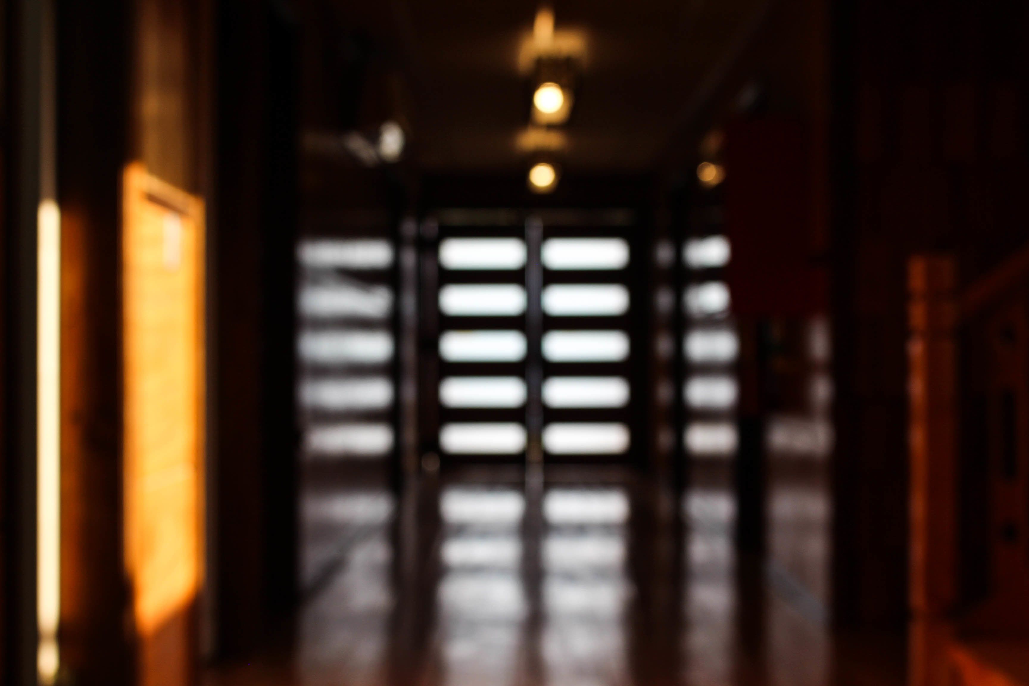 Corredor interior desfocado com várias janelas e um luminário.