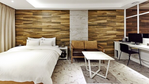 Quarto de hotel moderno com uma cama, uma escrivaninha e um espaço de estar.