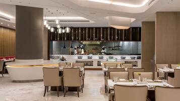 Restaurante moderno com área de bar central, diversas mesas de jantar e cozinha ao fundo.