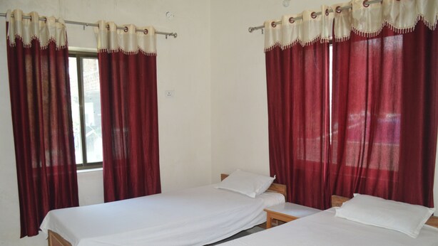 Quarto com duas camas de solteiro, cortinas vermelhas e uma janela.