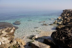 Litoral rochoso com águas cristalinas e vista para o mar.