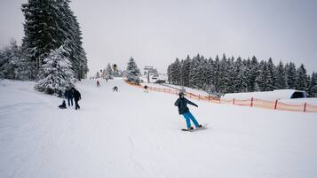 Pista de esqui nevada com pessoas praticando esqui e snowboard.
